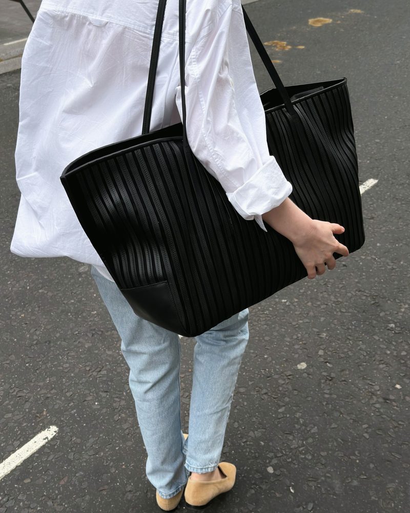 Classic black tote bag with ribbed texture%2C effortlessly paired with a white oversized shirt and light denim jeans%2C perfect for weekend outings