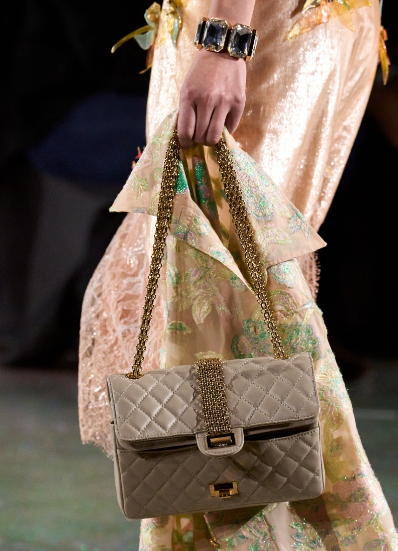 Chanel beige quilted shoulder bag with gold chain straps, styled with a shimmering floral runway dress