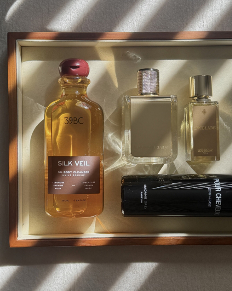 Perfume layering set with Silk Veil oil body cleanser%2C glass fragrance bottles and hair mist arranged in sunlit tray