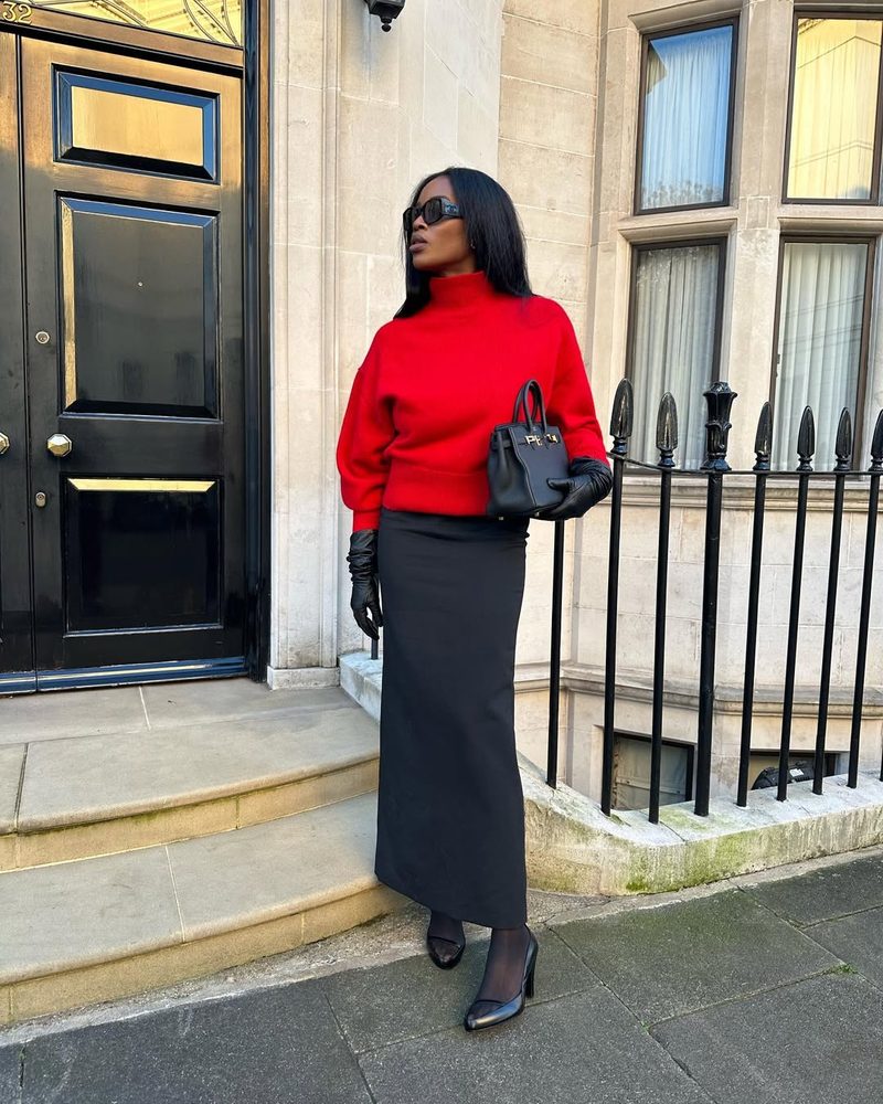 Chic red knit sweater paired with a sleek black pencil skirt%2C classic black gloves%2C and stylish heels%2C effortlessly elegant against a city backdrop