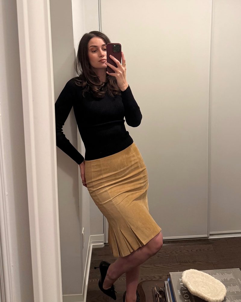 Ribbed black long-sleeve top paired with a tan suede pencil skirt featuring a flared hem%2C complemented by black pointed-toe heels