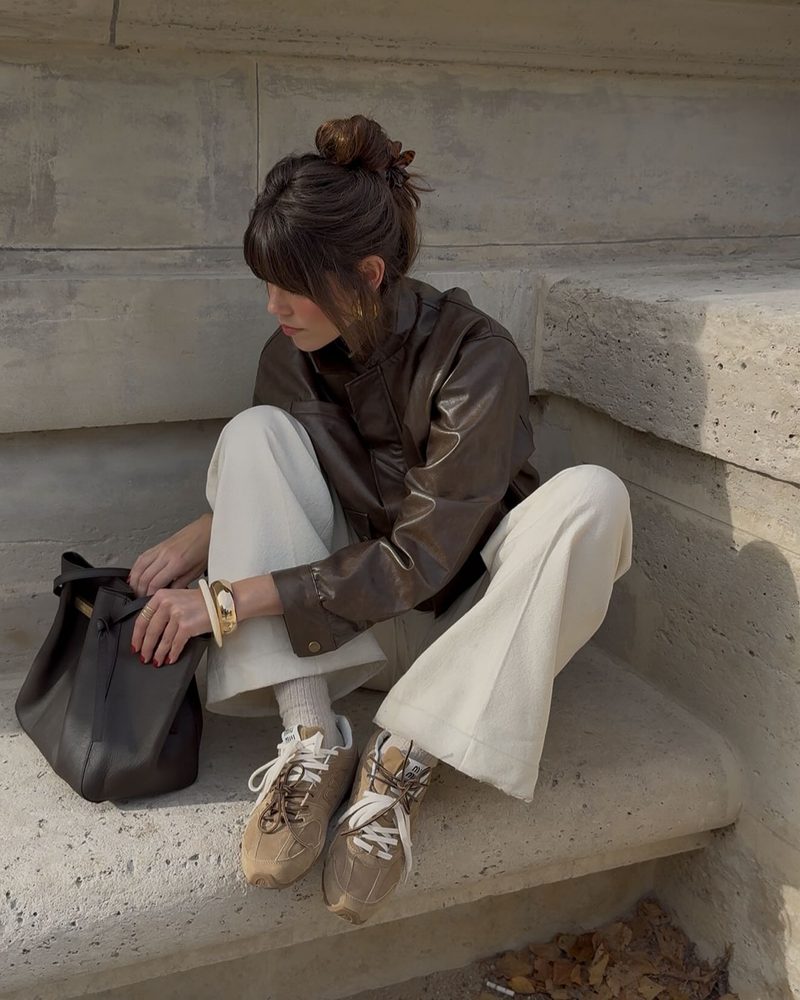 Chic look featuring a brown leather jacket%2C cream wide-leg pants%2C beige sneakers%2C and a black tote bag%2C styled for a modern autumn aesthetic