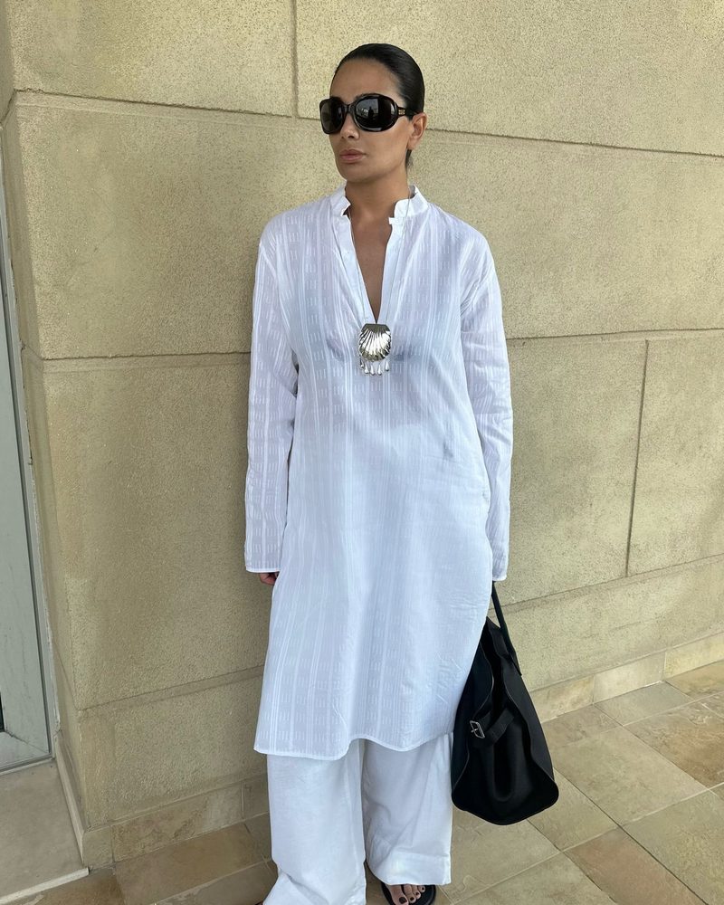 Chic summer ensemble featuring a long white tunic with subtle textural details%2C paired with loose white pants and oversized sunglasses
