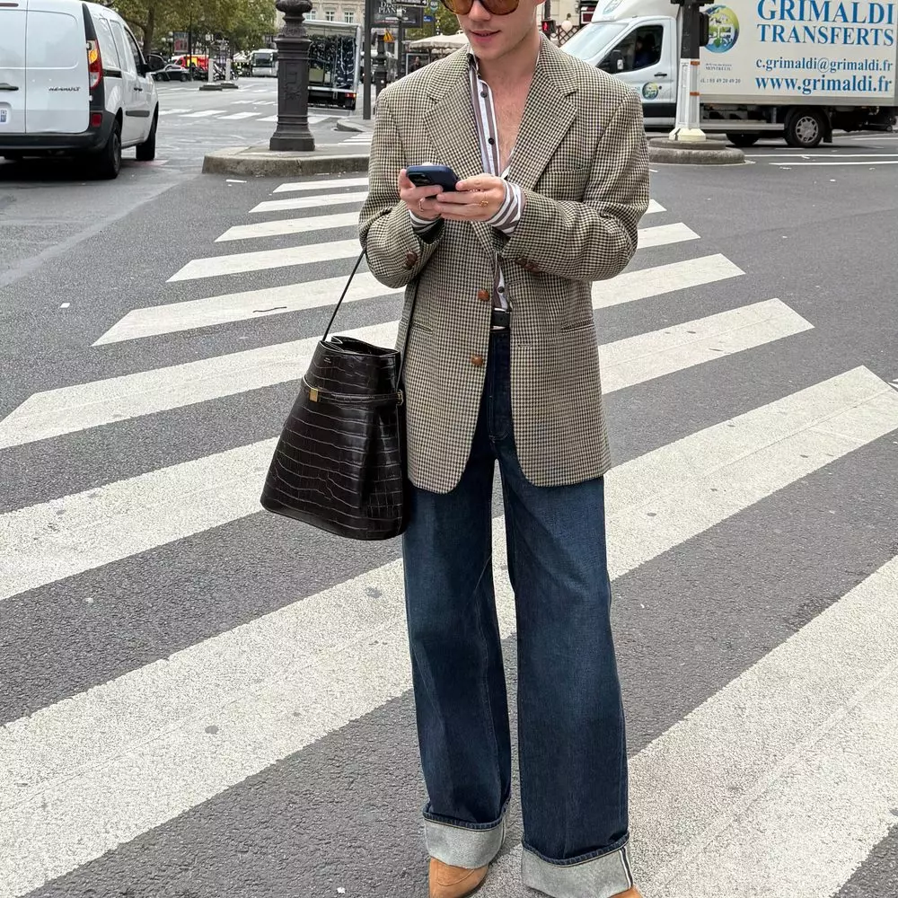 Oversized plaid blazer paired with wide-leg denim jeans, stylishly accessorized with large sunglasses and a chic croc-embossed handbag