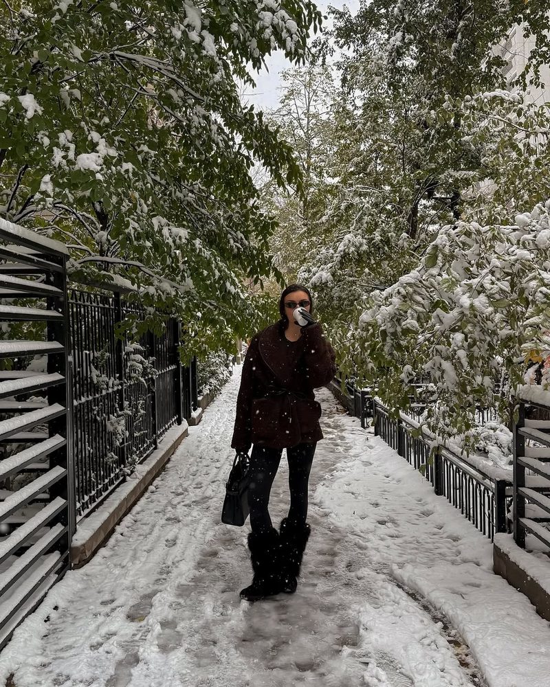 Cozy brown oversized wrap coat paired with chic black leggings and stylish black faux fur boots%2C set against a snowy landscape.