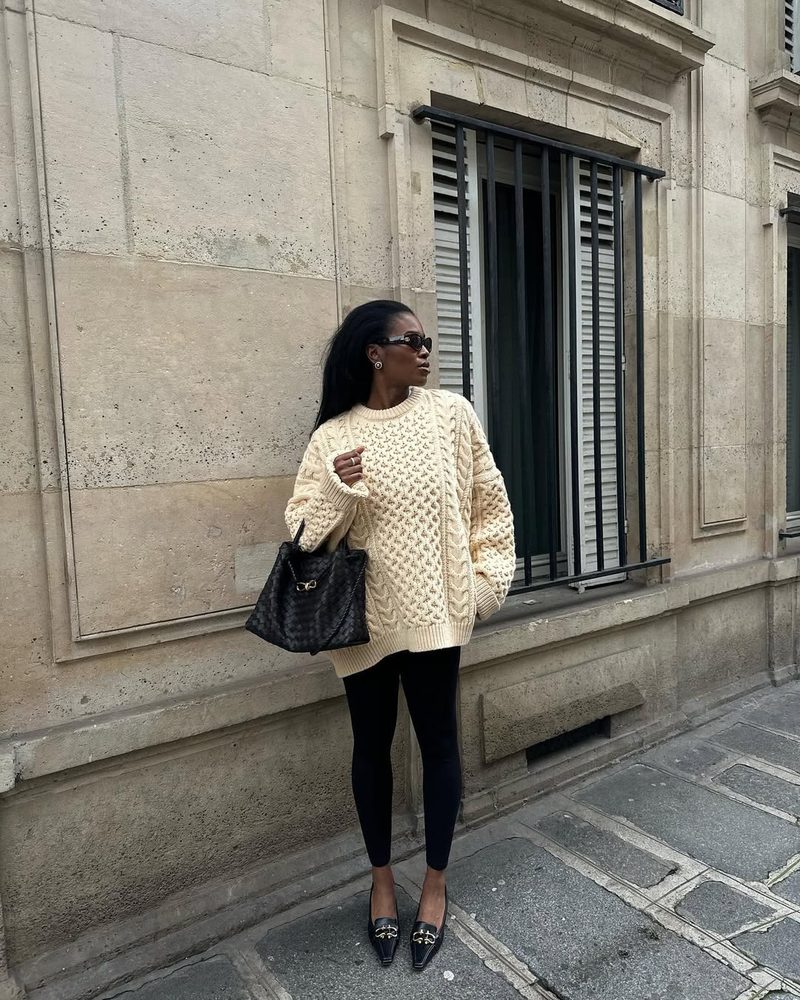 Cozy cream cable-knit sweater paired with black leggings%2C complete with chic black pointed-toe flats and a structured tote bag%2C perfect for date night.