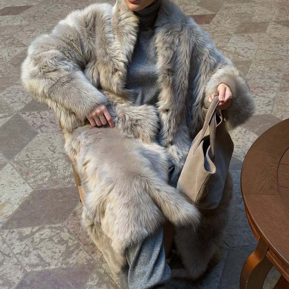 Luxurious faux fur winter coat paired with a gray turtleneck, soft knit pants, and beige heeled mules, elegantly styled for casual winter outings