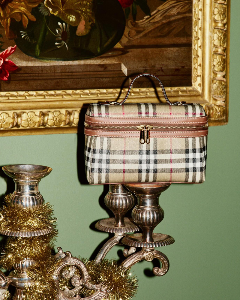 Burberry check vanity case with tan leather trim displayed on ornate silver candlesticks beneath a gilded painting for a luxe holiday setting