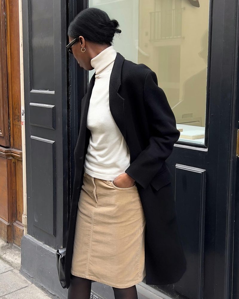 Elegant monochrome outfit featuring a tailored black overcoat%2C cream turtleneck%2C and beige pencil skirt%2C accentuated by chic sunglasses and a sleek handbag.%0A%0A%0A%0A%0A%0A%0A%0A