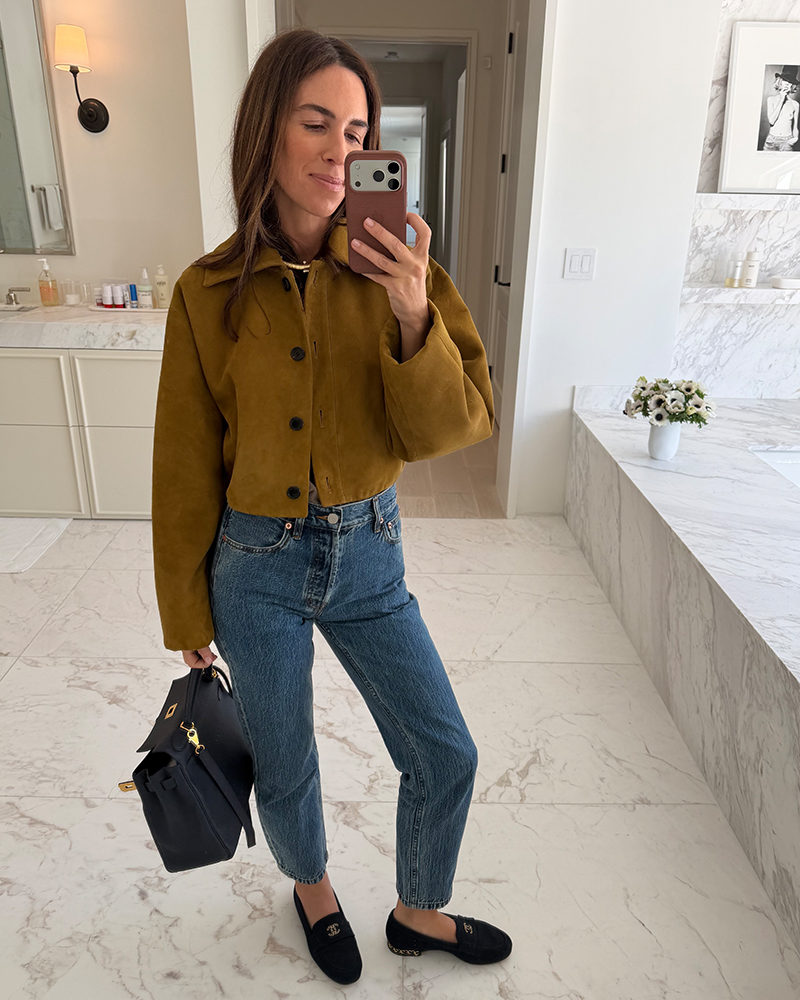 Girl wearing denim jeans with suede jacket and black handbag