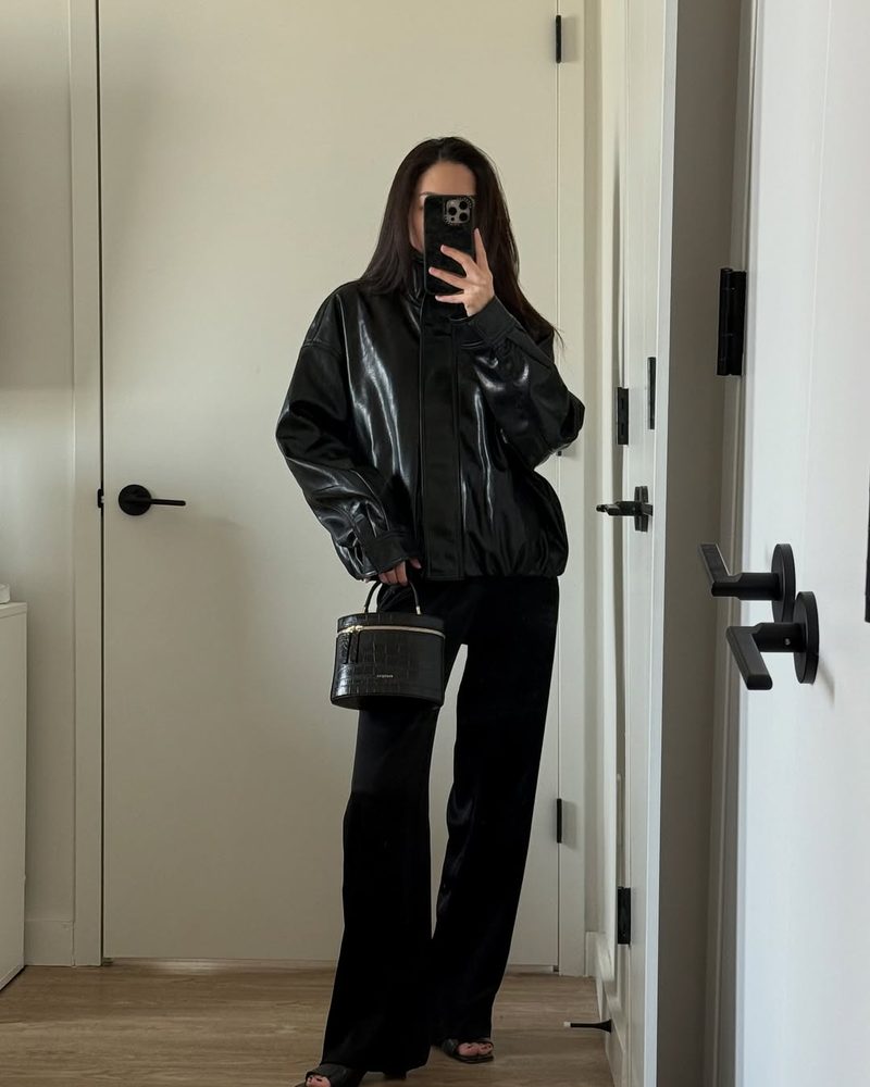 Oversized black faux leather jacket paired with wide-leg black trousers and a chic structured handbag%2C styled for a modern%2C sophisticated look