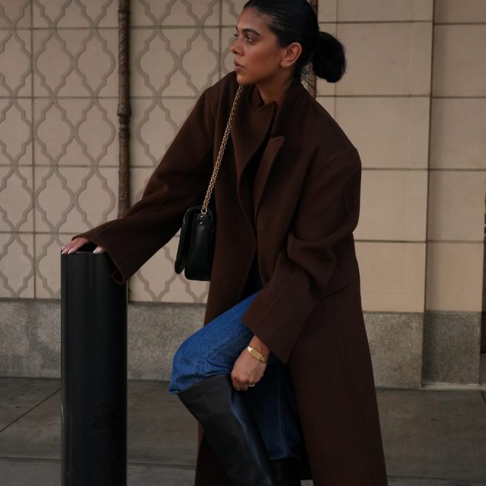Chic knee-high boots in sleek black leather paired with a stylish brown oversized coat and classic blue denim, exuding effortless elegance.