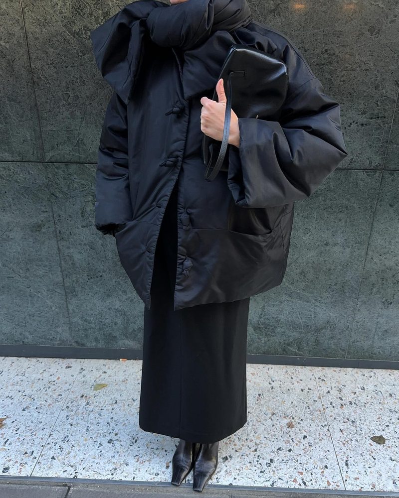 Chic black puffer coat styled with a matching scarf%2C paired with an elegant black midi skirt and sleek ankle booties for a modern winter look