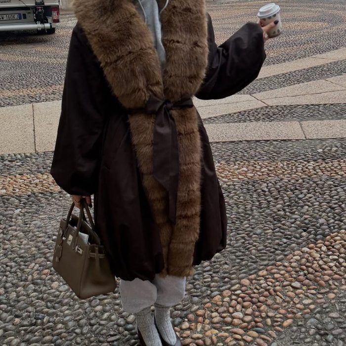 Chic brown wrap coat with a luxurious fur collar, paired with gray trousers and pointed-toe heels, accessorized with a structured handbag.