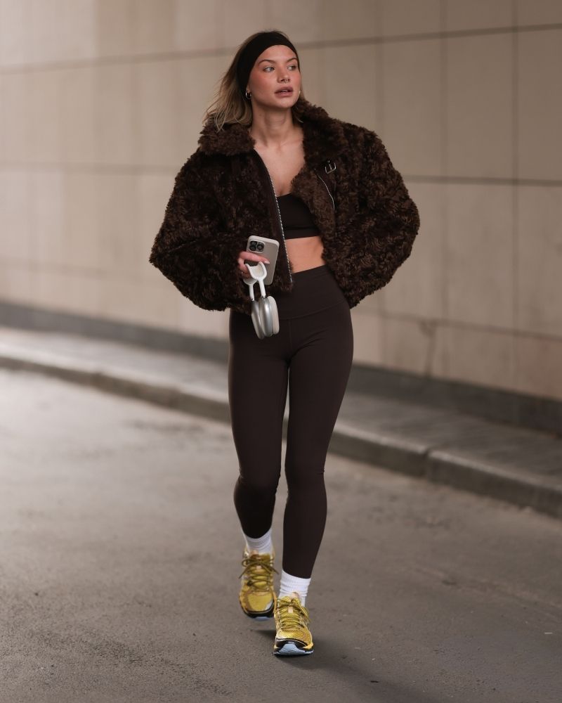 Model in brown faux fur jacket and matching leggings with yellow sneakers%2C styled for off-duty street look
