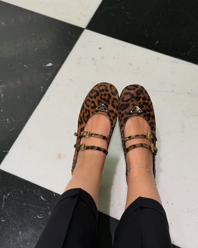 Prada leopard-print Mary Jane flats with gold buckles%2C styled with black trousers on a checkered tile floor