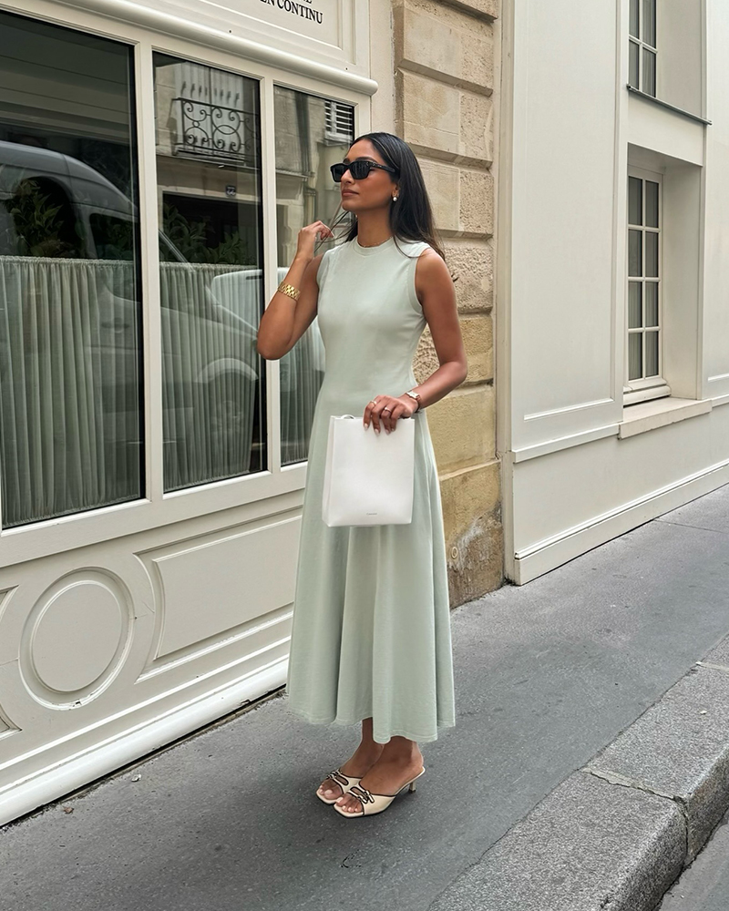 Street style look wearing a mint green sleeveless midi dress with white clutch and sandals%2C styled on a Parisian sidewalk