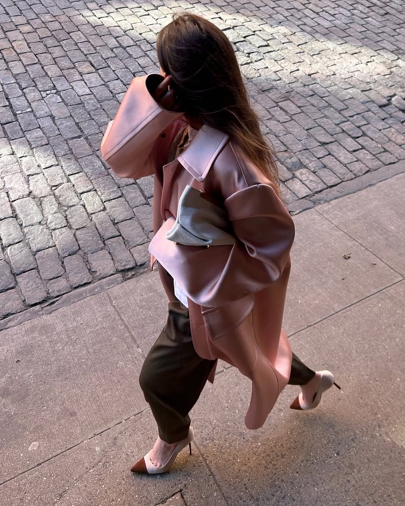 Blush satin trench coat styled with slim black trousers%2C pointed heels%2C and a clutch for an elegant street style outfit