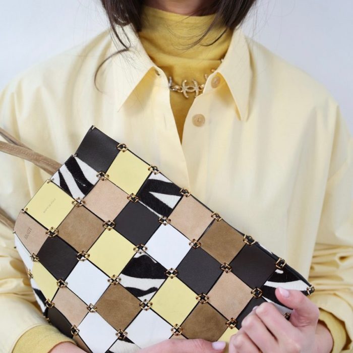Chic spring outfit featuring a pale yellow oversized shirt layered over a turtleneck, paired with a statement woven tote bag and stylish sunglasses.