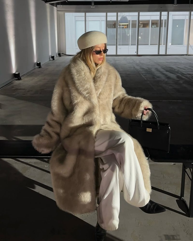 Luxurious oversized faux fur coat paired with crisp white trousers%2C chic black handbag%2C and a stylish cream beret at CPHFW