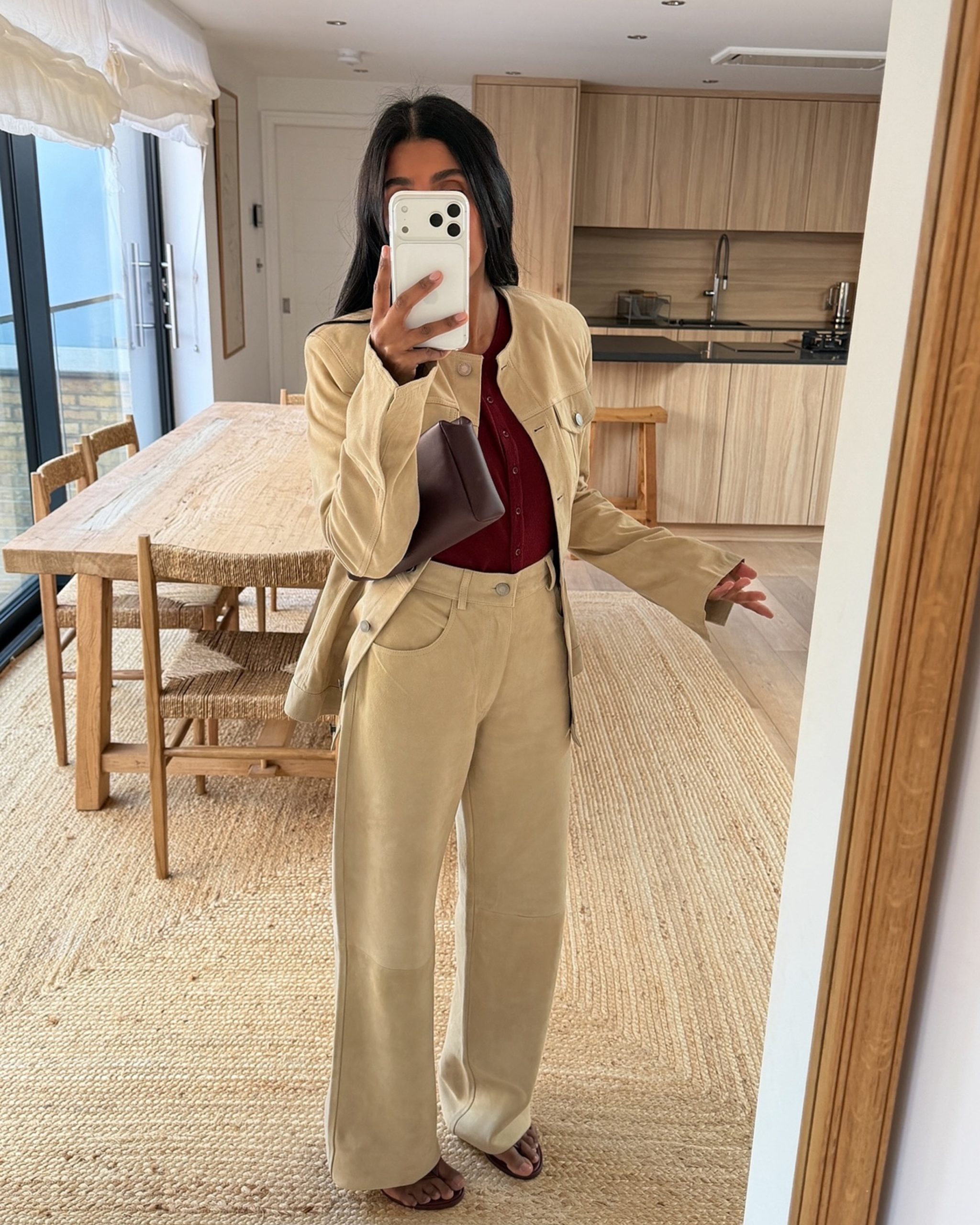 Beige denim outfit featuring a tailored jacket and wide-leg pants paired with a burgundy top%2C complemented by a stylish shoulder bag