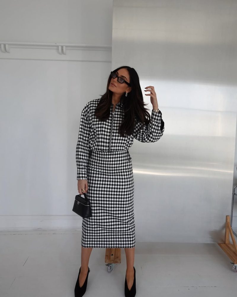 Black and white gingham midi dress styled with cat-eye sunglasses%2C mini top-handle bag and pointed pumps in a minimalist studio setting