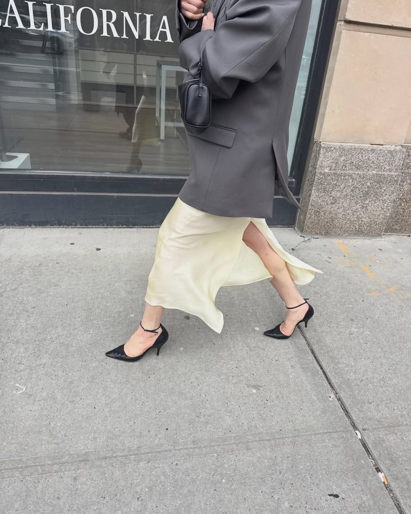 Cream silk slip skirt styled with oversized gray blazer%2C black kitten heels and mini shoulder bag for chic city outfit