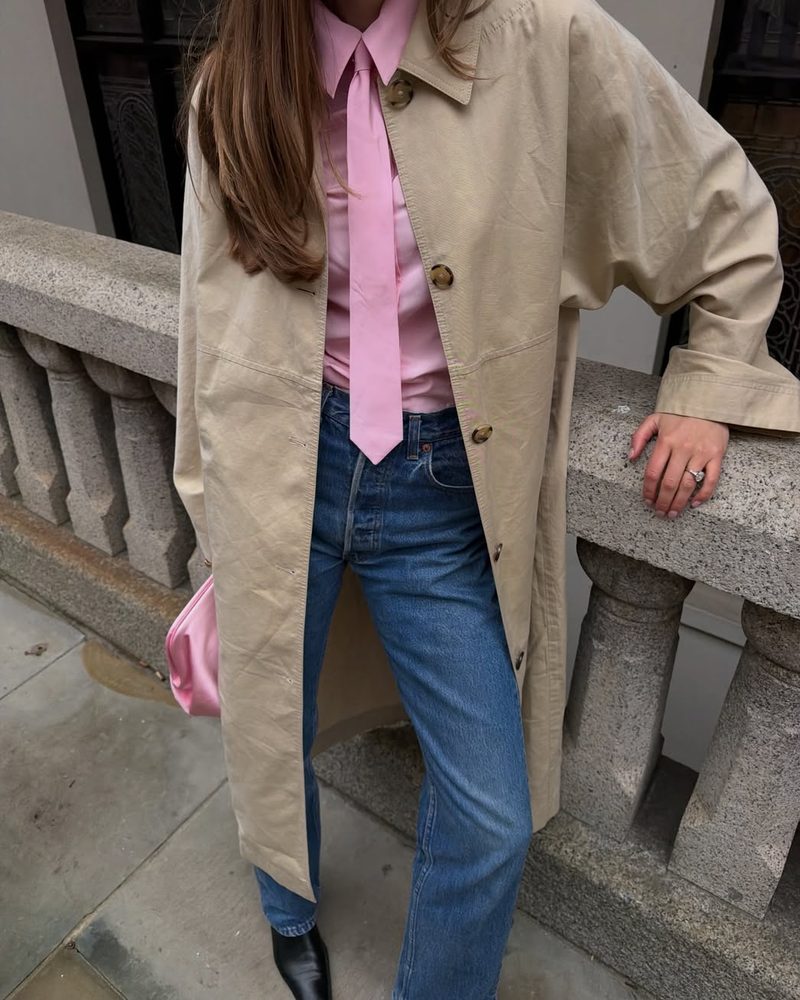 Beige trench coat styled with pink shirt and tie%2C blue straight leg jeans and mini pink bag for chic spring street style
