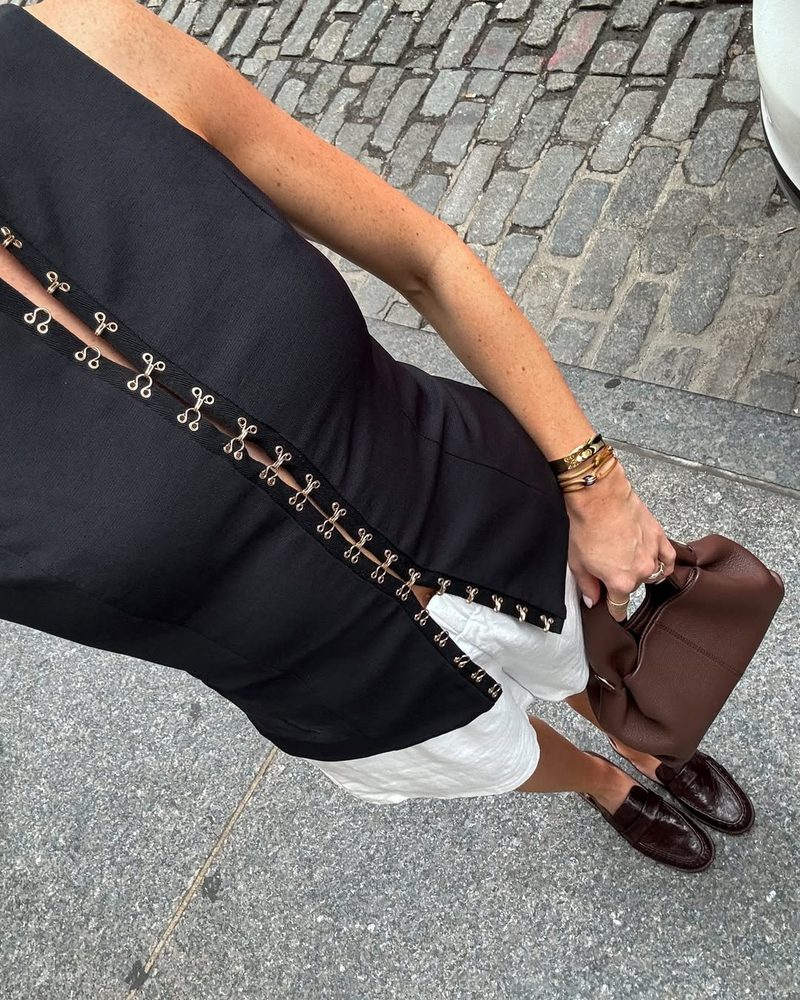 Black sleeveless hook-detail top with white shorts%2C styled with brown leather loafers and matching clutch for chic summer outfit