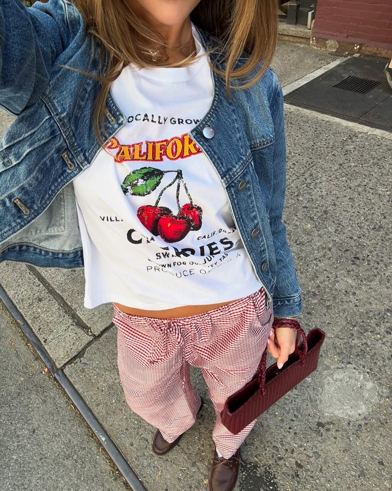 Denim jacket layered over graphic California cherries T-shirt with red gingham pants and mini bag for playful spring street style