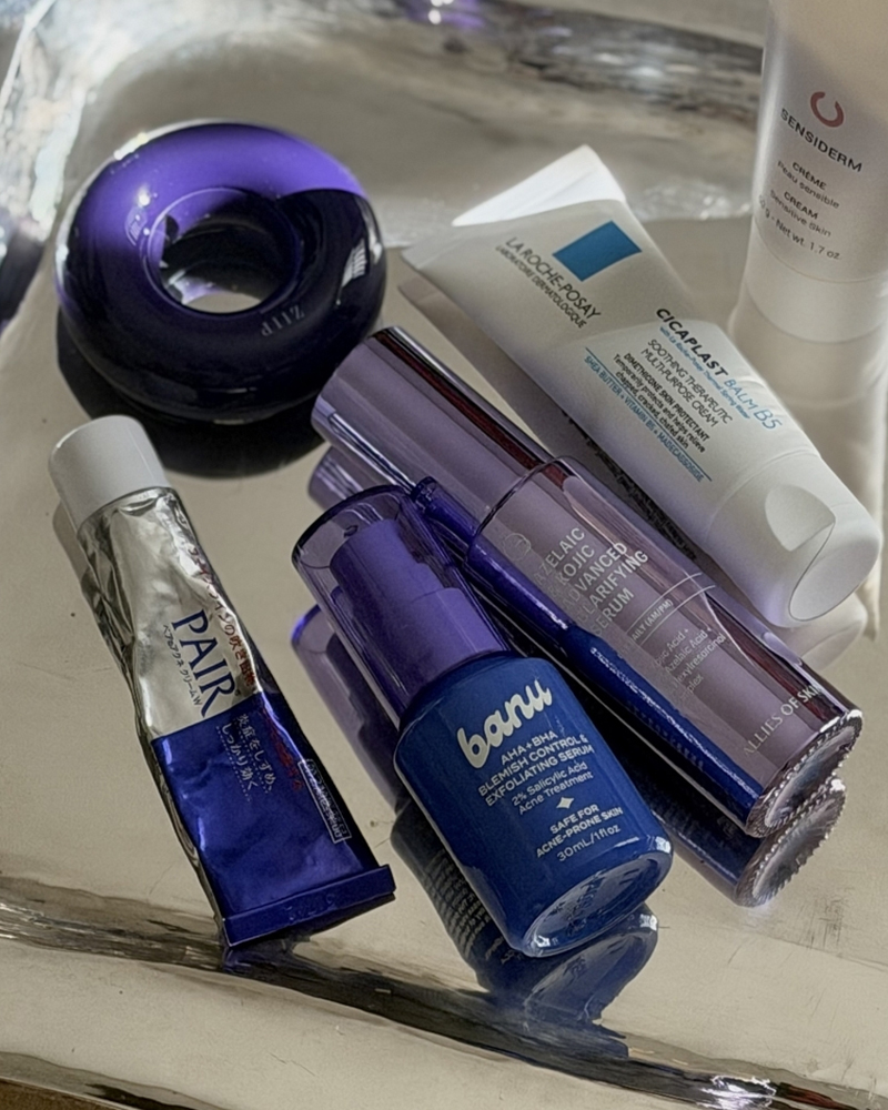 Skincare essentials including La Roche-Posay Cicaplast Balm B5%2C serum bottles and acne treatments arranged on reflective tray