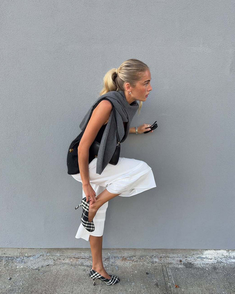 Black sleeveless top with white capri pants and plaid slingback heels%2C styled with sweater over shoulders for chic summer look