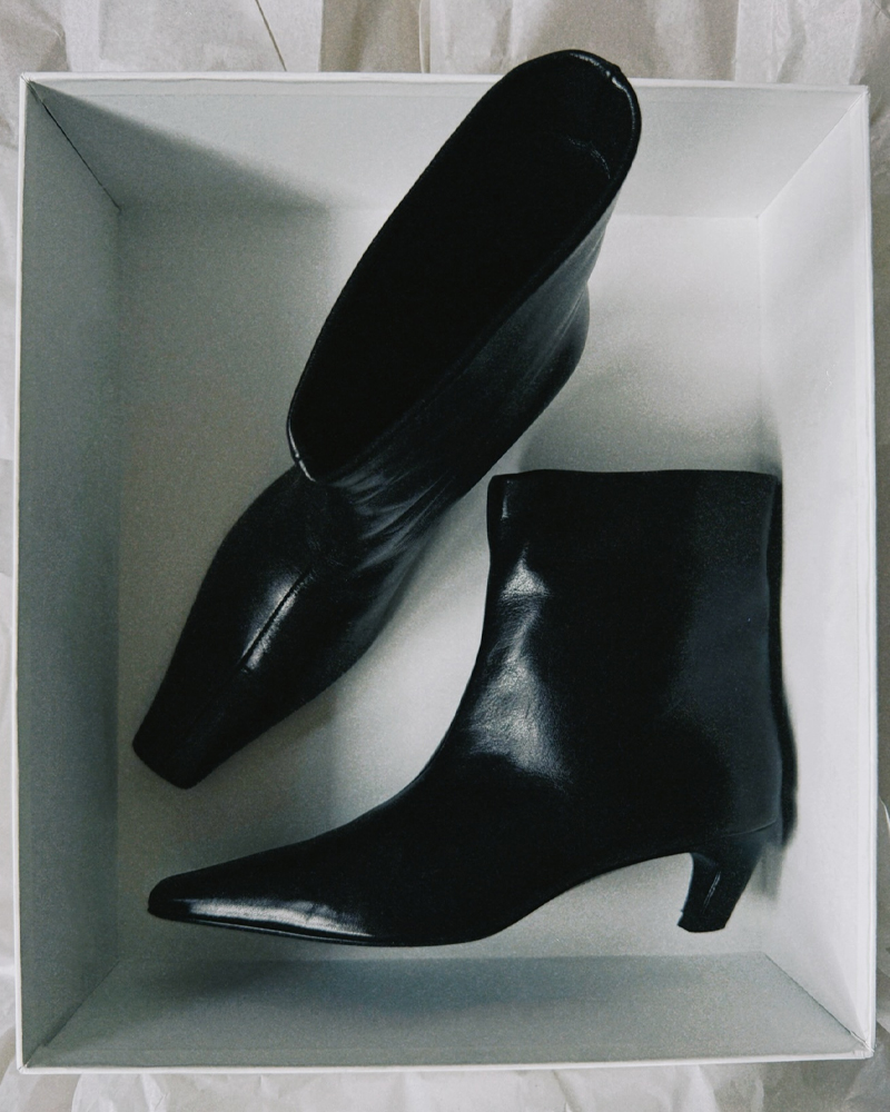 black leather ankle boots with pointed toes and low kitten heels in a white box