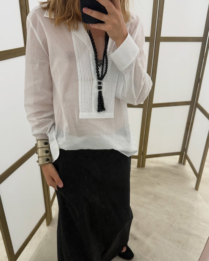 Relaxed look with sheer white pintuck blouse and black maxi skirt%2C styled with tassel necklace and cuff bracelet in fitting room