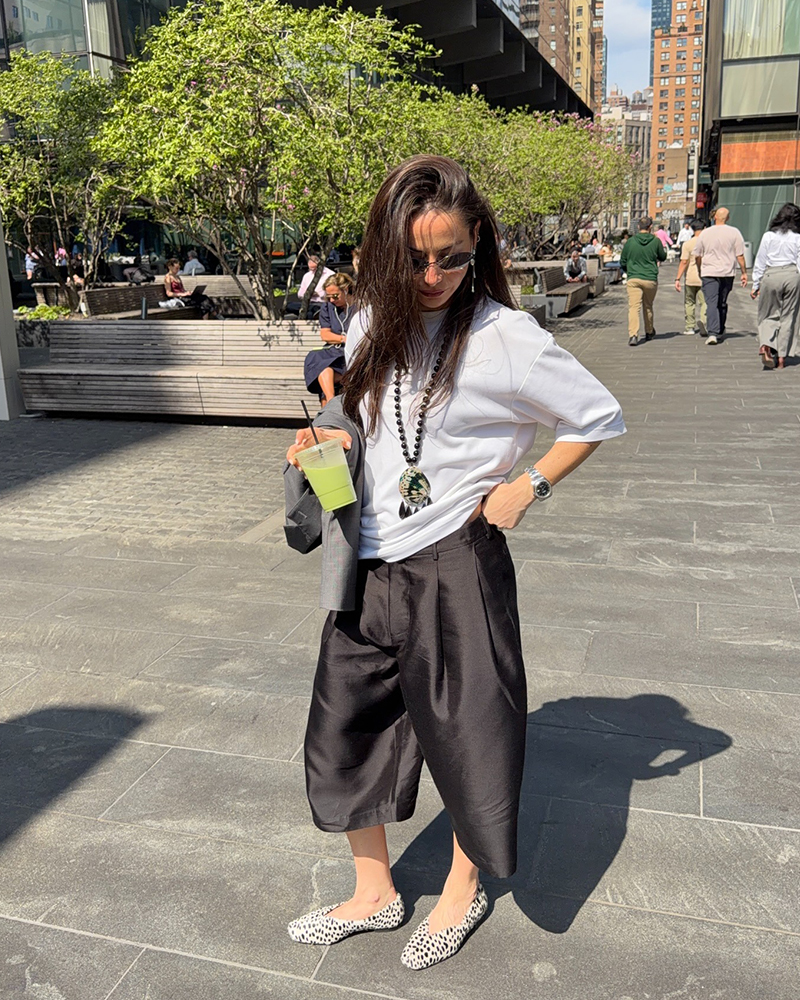 White T-shirt with black culottes%2C statement pendant necklace%2C flats and sunglasses styled on sunny city plaza