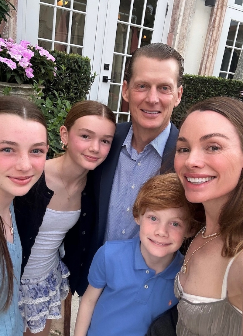 Family portrait with parents and children in casual spring outfits, styled outdoors in front of a classic home entrance