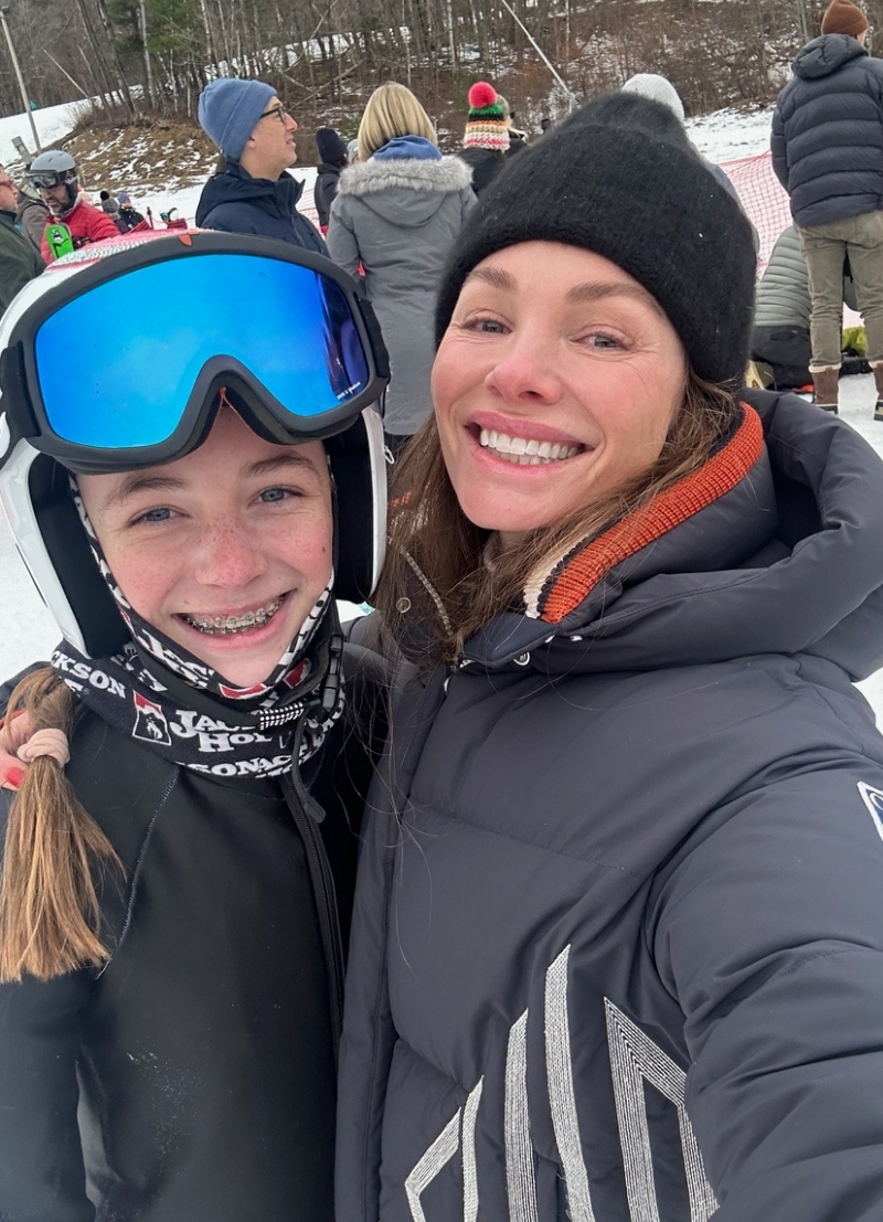 Mother and child in ski gear with helmets and puffer jackets, styled on a snowy slope during winter