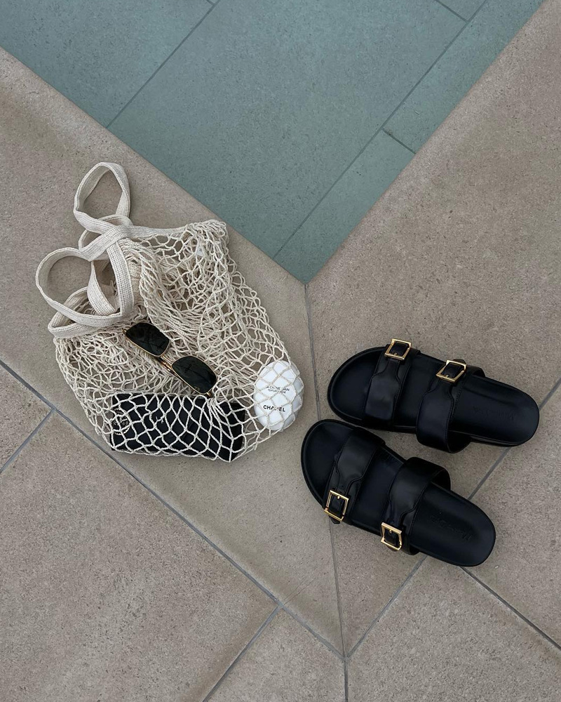 Chanel net tote bag with quilted pouch and sunglasses%2C paired with black leather buckle slides on tiled poolside floor