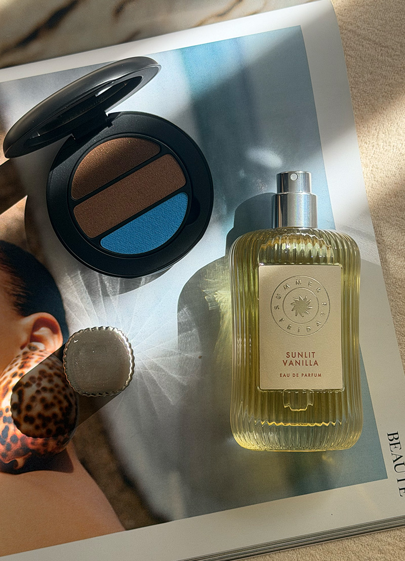 Summer Fridays Sunlit Vanilla eau de parfum with eyeshadow compact and beauty accessories, styled on an open magazine in soft natural light