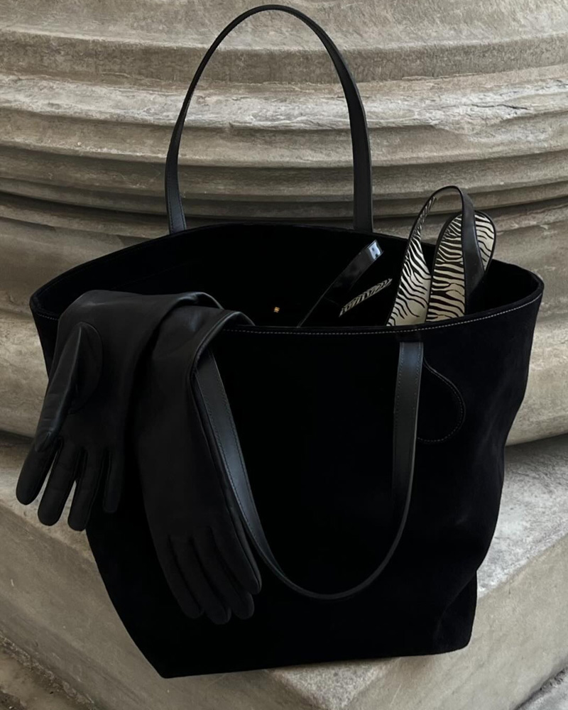 Black suede tote bag with leather handles styled with gloves and zebra print flats%2C set on stone steps