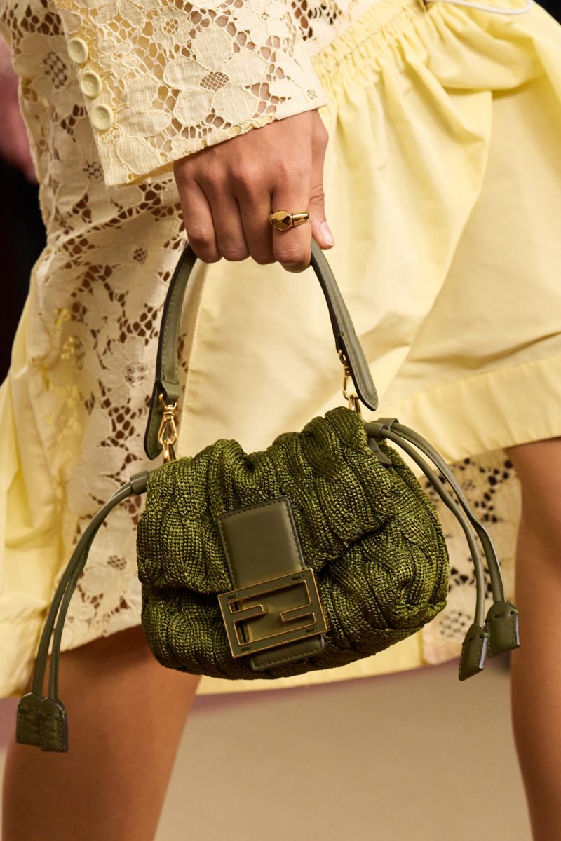 Fendi olive green raffia mini bag with FF logo clasp and drawstring sides, styled with a delicate yellow lace dress