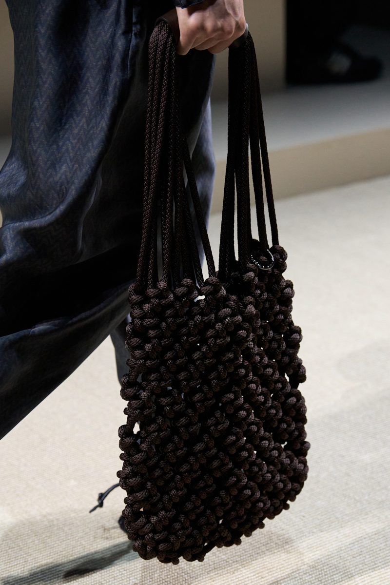 Dark brown knotted rope tote bag with chunky texture and drawstring straps paired with a sleek satin skirt outfit