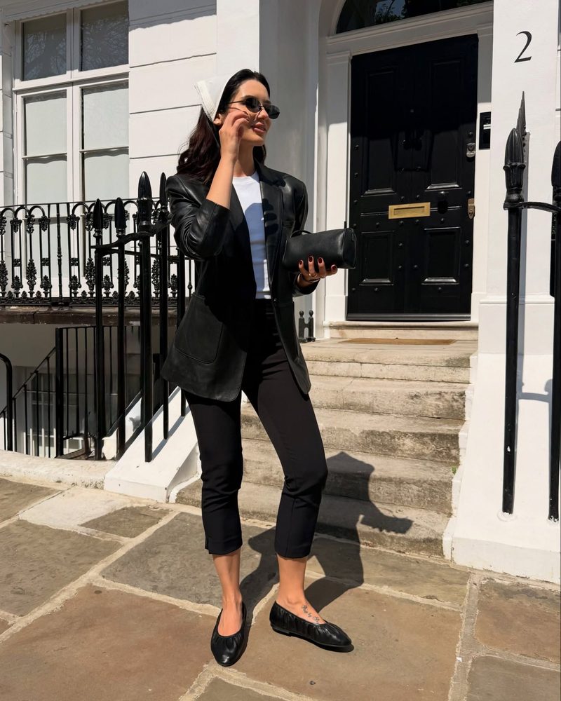 Chic look featuring a black leather blazer over a white top%2C paired with fitted black capris and stylish black flats%2C perfect for a sunny day out