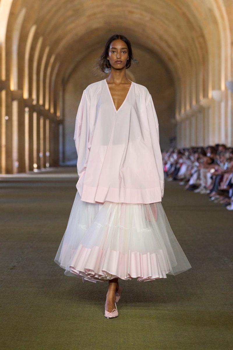 Jacquemus spring summer 2026 oversized pale pink blouse with deep v-neck paired with layered tulle midi skirt and matching ballet flats