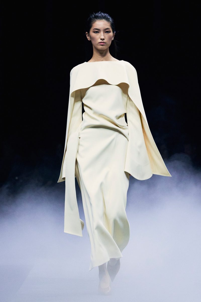 Khaite spring 2026 ivory long-sleeve gown with dramatic cape detail and flowing silhouette on runway