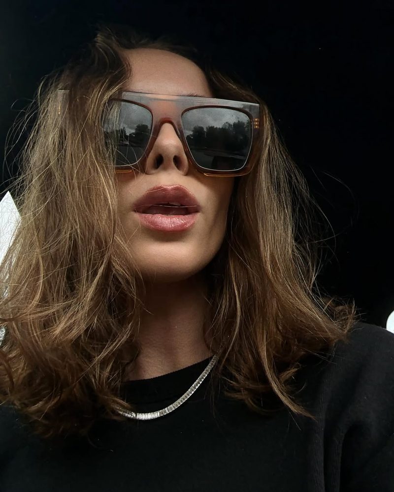 Oversized square sunglasses with tinted lenses paired with black top and silver chain necklace for modern street style look