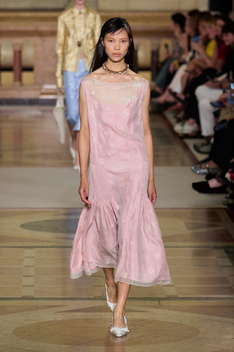 Model wearing Tory Burch sleeveless pink midi dress with sheer neckline and delicate embroidery on runway