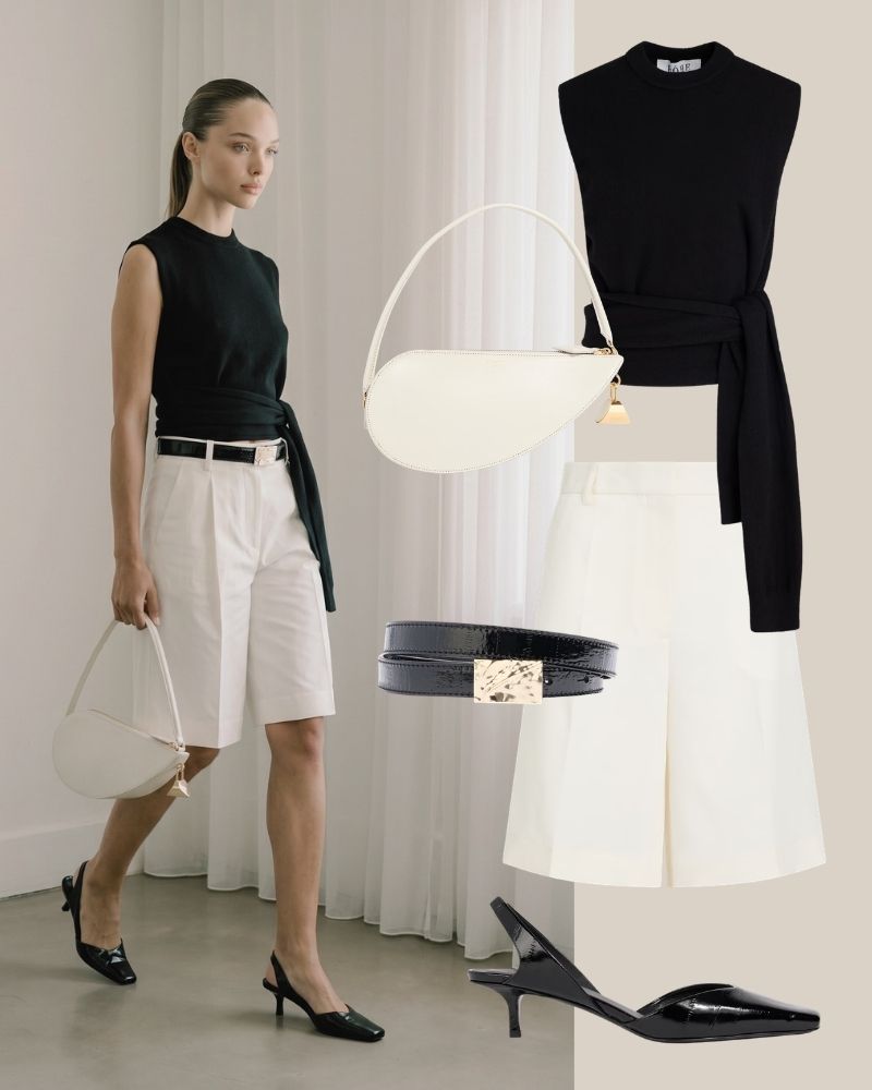 Model in a black sleeveless wrap top and white tailored shorts with a white shoulder bag and black slingback heels in a minimalist studio