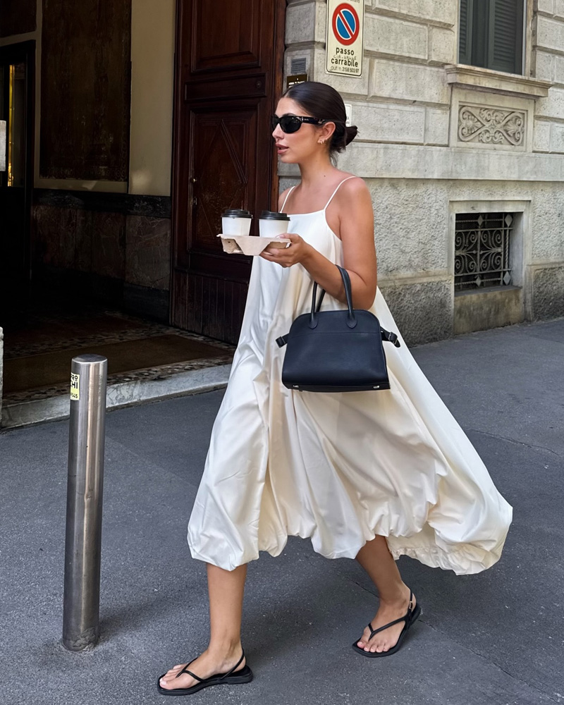 White balloon midi dress with black thong sandals and structured leather tote on a European city street