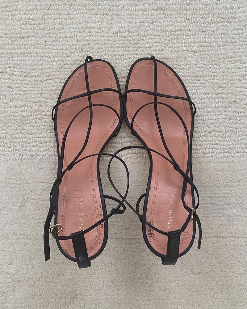 Celine strappy leather sandals with minimalist black lace-up straps and blush footbeds%2C photographed on a textured cream rug